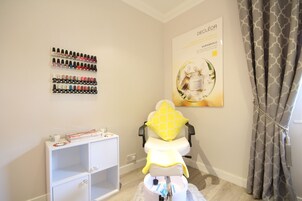 Um banheiro com uma cadeira, uma prateleira com esmalte e um pôster na parede.