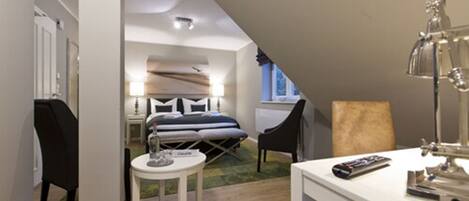 Quarto de hotel moderno com cama, escrivaninha, cadeira e abajur.
