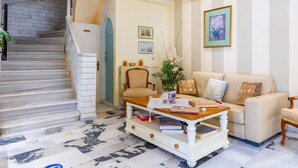 Uma sala de estar com escada, sofá, mesa de centro e um candelabro.