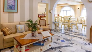 Uma sala de estar com sofá, mesa de centro e um espaço de refeições com cadeiras e mesa.