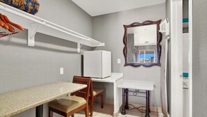 Quarto compacto com cozinha compacta, área de refeições com mesa e cadeiras, um espelho e uma cama.