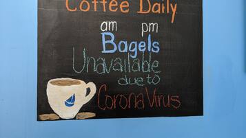 Um aviso com o texto: 'Café diariamente, abre e fecha. Bagels indisponíveis devido à Coronavirus.'