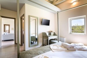 Quarto de hotel com cama, escrivaninha, televisão e janela com vista.