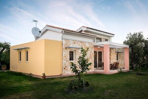 Uma casa de dois andares com antena parabólica, fachada de pedra e varanda coberta com móveis de exterior.