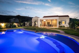 Uma casa moderna com piscina, um pátio e uma entrada bem iluminada.