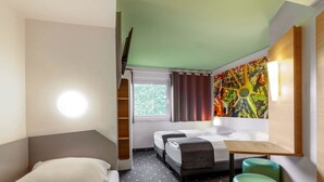 Quarto de hotel com cama, duas mesas de cabeceira, escrivaninha, cadeira e janela com cortinas.