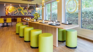 Um restaurante moderno com um balcão comprido, cadeiras amarelas e bancos verdes.