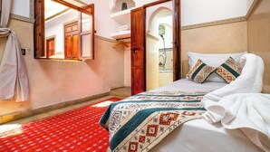 Quarto com cama, espelho grande, guarda-roupa e banheiro visível através de uma porta aberta.