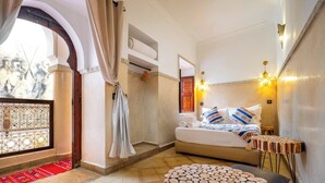 Quarto de hotel com cama, mesa redonda pequena, janela com cortinas e vista para o exterior.