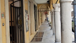 Corredor com piso de pedra, paredes amarelas e colunas.