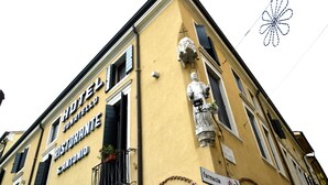 Um hotel com fachada amarela, uma estátua e uma placa indicando que é um restaurante.