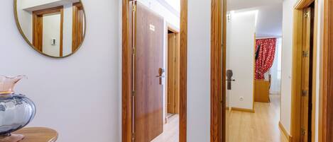 Um corredor com portas de madeira, um espelho e uma mesa com um vaso.