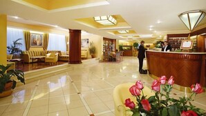 Um saguão de hotel com balcão de recepção, área de estar e uma janela grande.