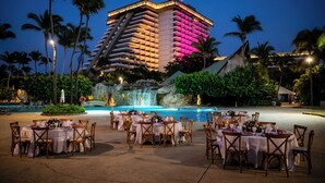 Hotel com piscina, área de refeições ao ar livre e uma cascata.
