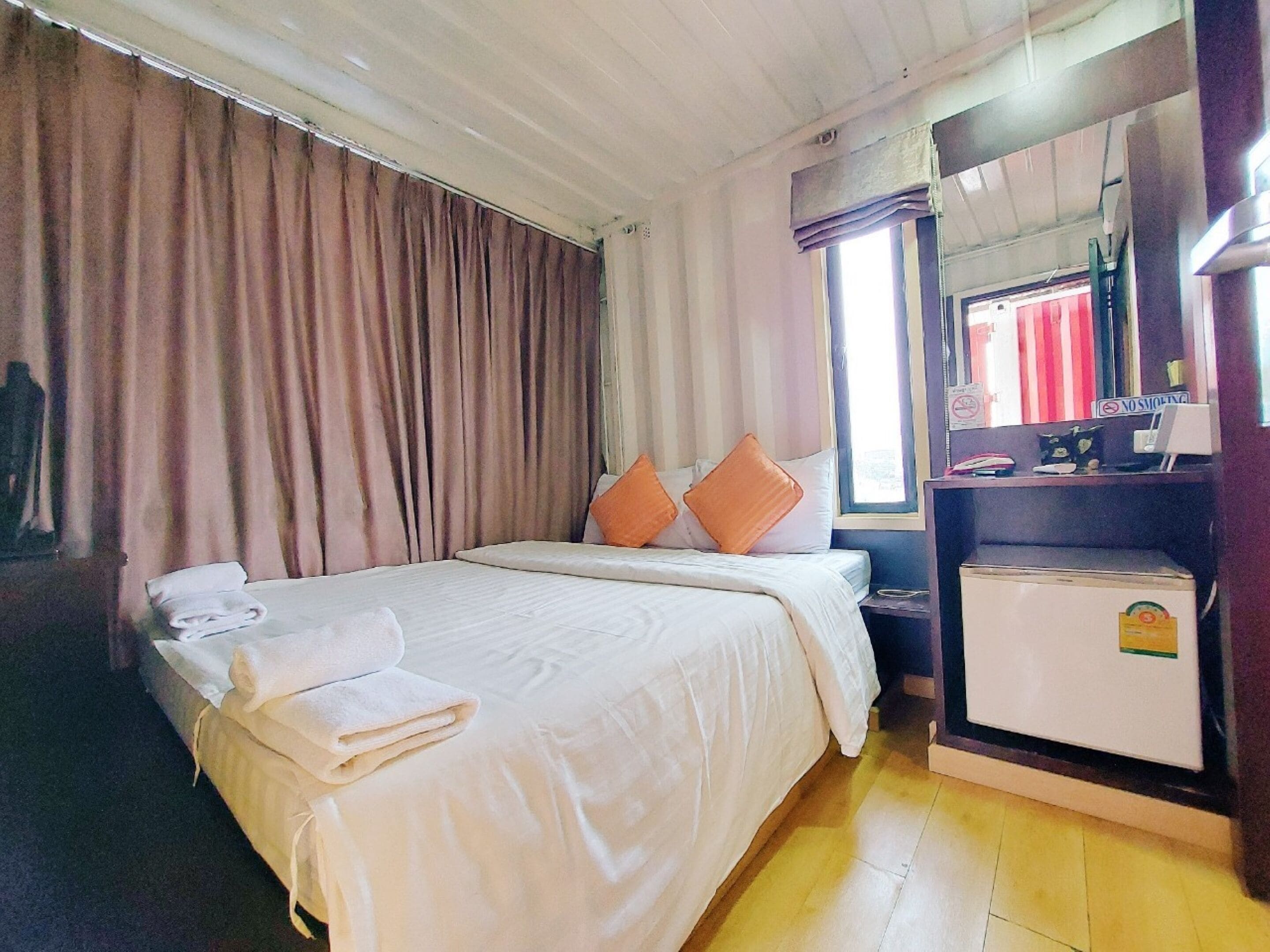 Quarto de hotel com cama, almofadas, escrivaninha e espelho.