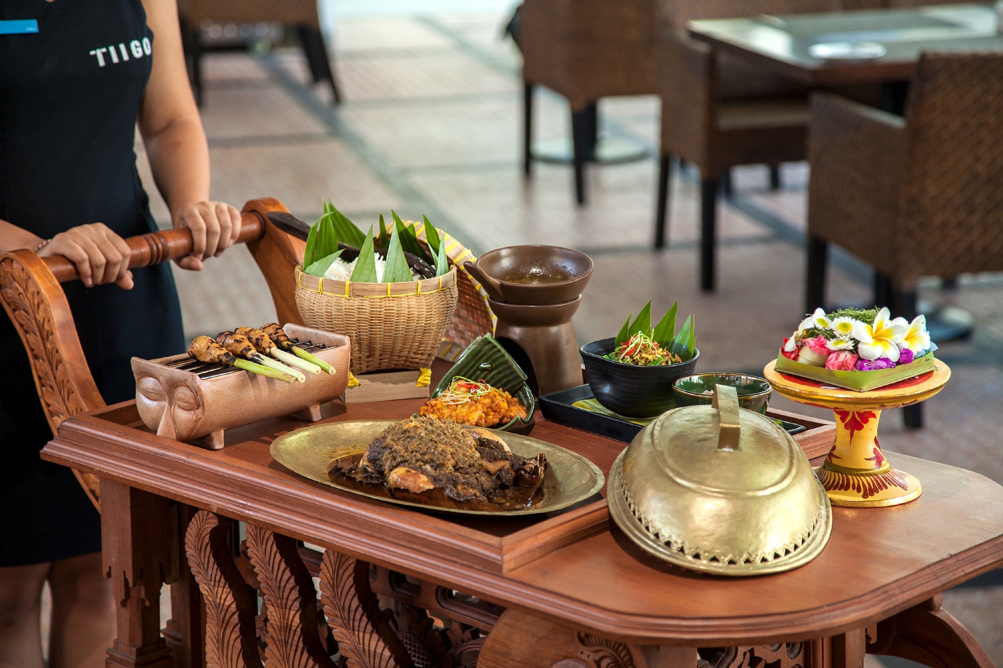 Uma mesa de madeira com diversos pratos, incluindo carne grelhada e uma decoração floral.