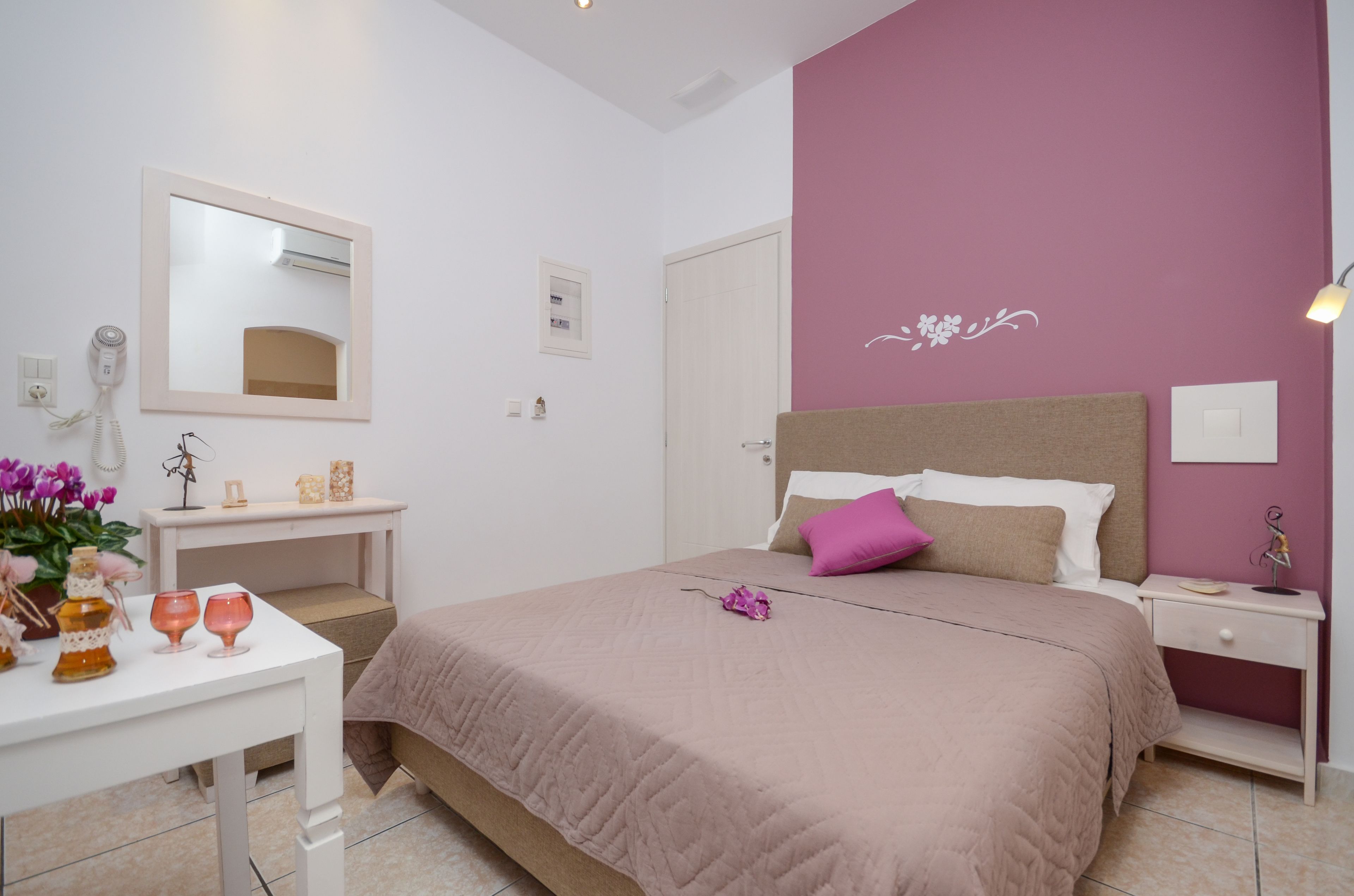 Quarto com cama, mesa de cabeceira, escrivaninha e secretária com espelho.