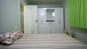 Quarto com cama, guarda-roupa e espelho.