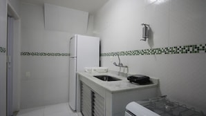 Uma cozinha compacta com geladeira, pia e fogão.