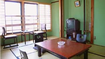 Um quarto em estilo japonês tradicional com tatames, uma mesa baixa e uma televisão.