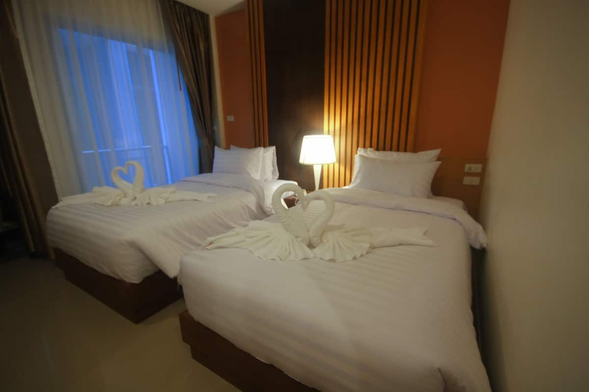 Quarto de hotel com duas camas, cada uma decorada com um arranjo de toalha em formato de cisne.