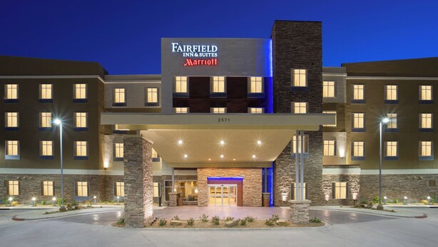 Um hotel Fairfield Inn & Suites Marriott de vários andares, com entrada destacada, fachada de pedra e sinalização iluminada.