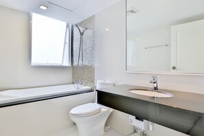 Um banheiro moderno com vaso sanitário branco, pia com bancada preta e um espelho grande.