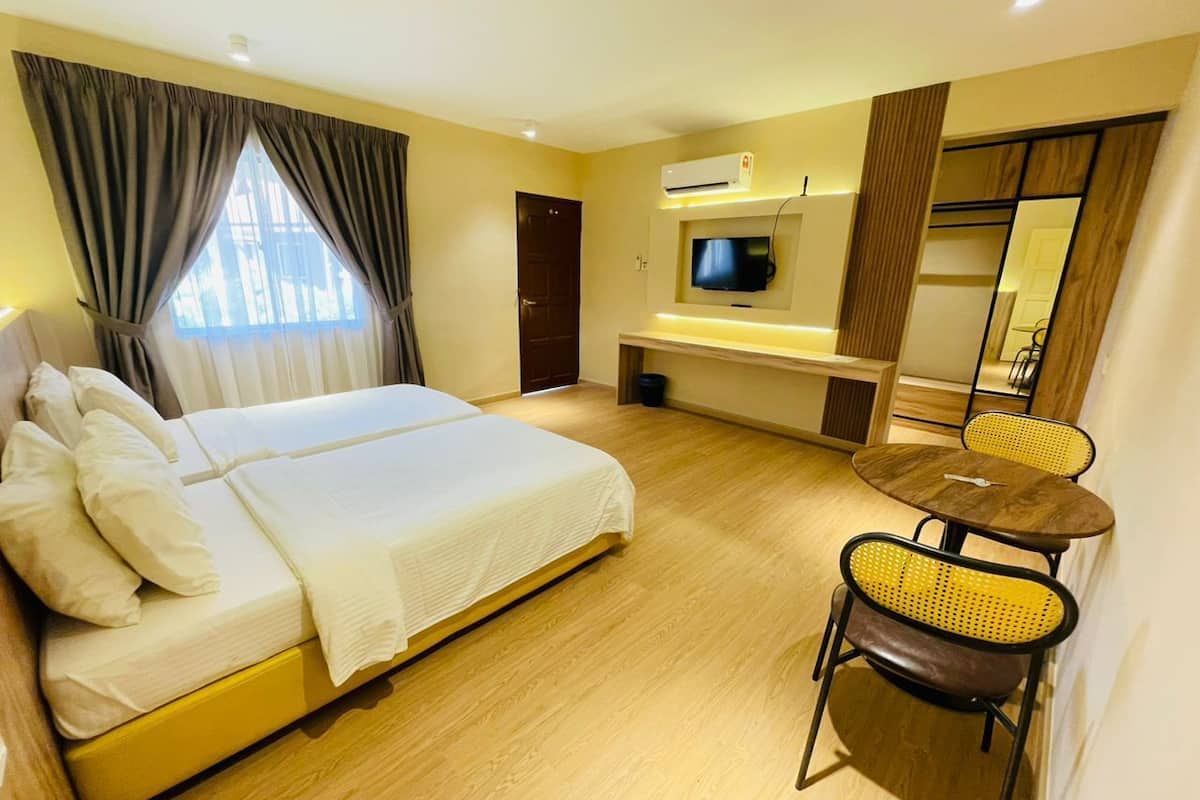 Quarto de hotel com uma cama, uma mesinha com cadeiras, uma televisão e um espelho.