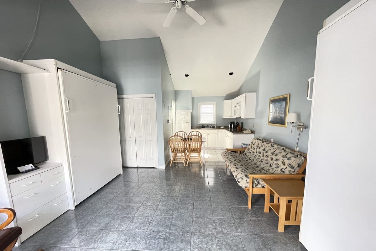 Um espaço compacto com cozinha compacta, área de refeições e sala de estar com sofá e cadeiras.