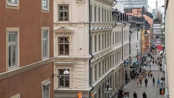 Uma praça urbana movimentada com edifícios históricos, um hotel de destaque e um edifício moderno de vidro ao fundo.