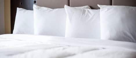 Uma cama com roupa de cama branca e cabeceira.