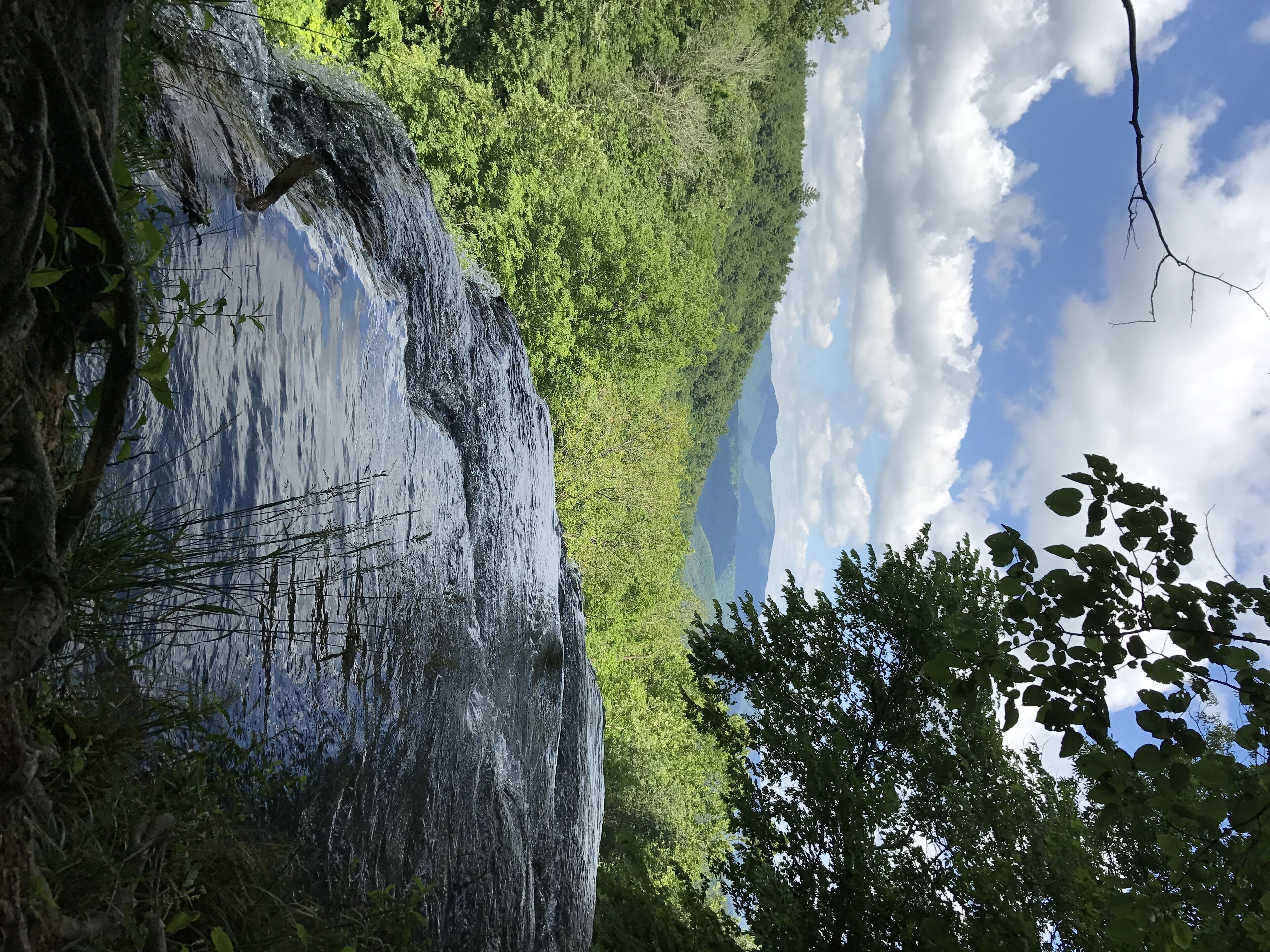 Paisagem natural com uma grande formação rochosa, vegetação densa e céu claro.
