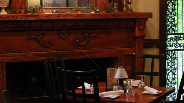 Uma sala de jantar com mesa de madeira, cadeiras e um espelho sobre a mesa.