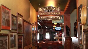 Corredor que leva a uma área de restaurante e bar, com quadros nas paredes.