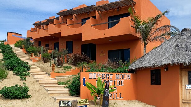 Um edifício com uma placa indicando 'Desert Moon Uptide Bar & Grill' e uma placa de 'Happy Hour'.