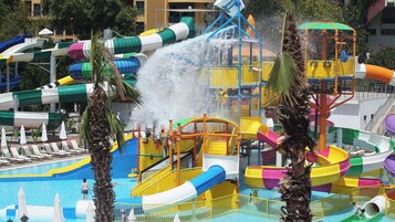 Um parque aquático com várias escorregas e atrações aquáticas, cercado por palmeiras e uma área de piscina.