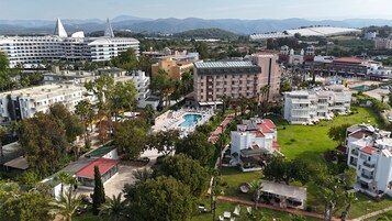 Um resort com piscina, vários edifícios e montanhas ao fundo.