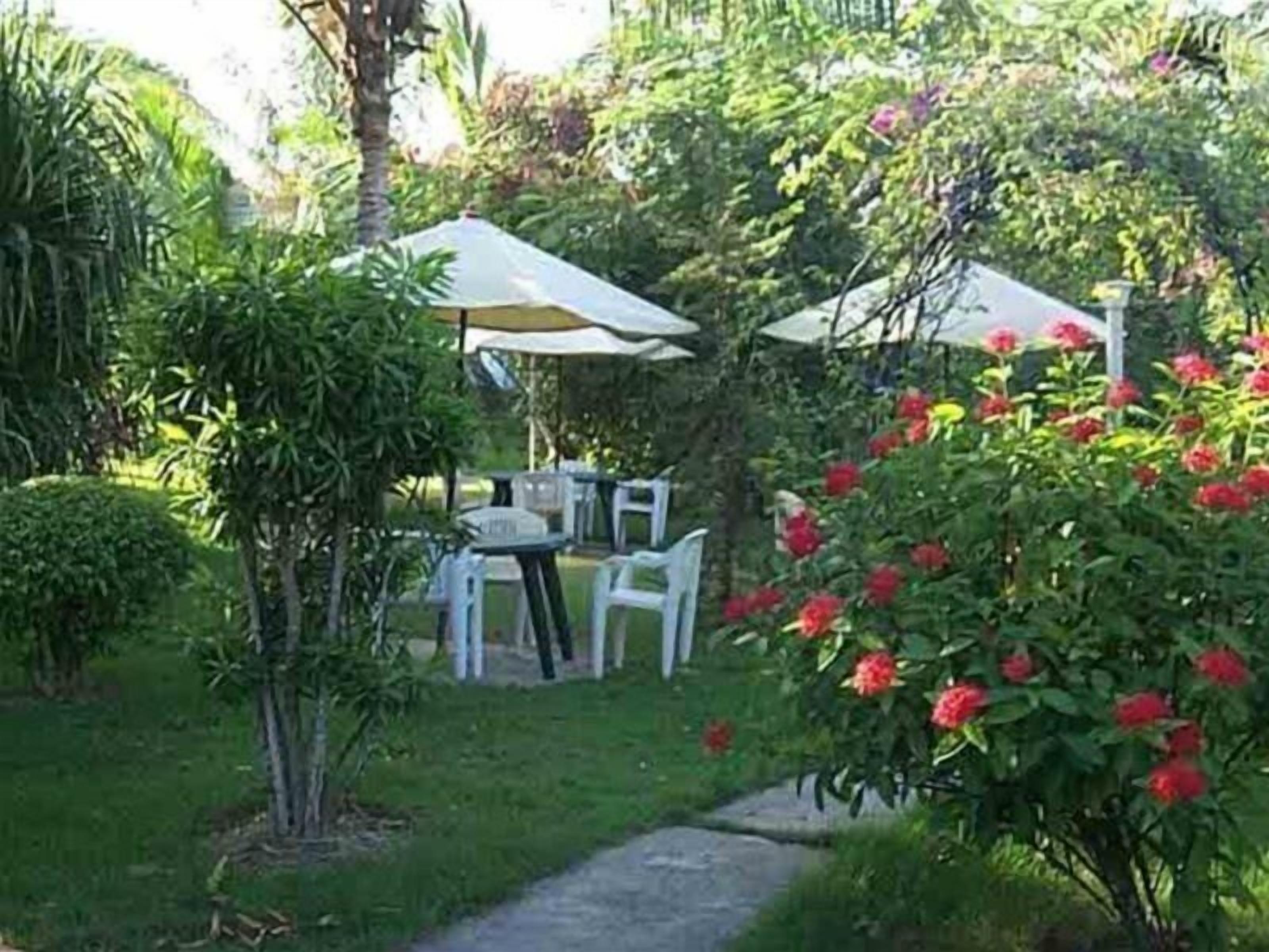 Um jardim com um caminho, área de estar ao ar livre e uma pequena mesa com cadeiras.