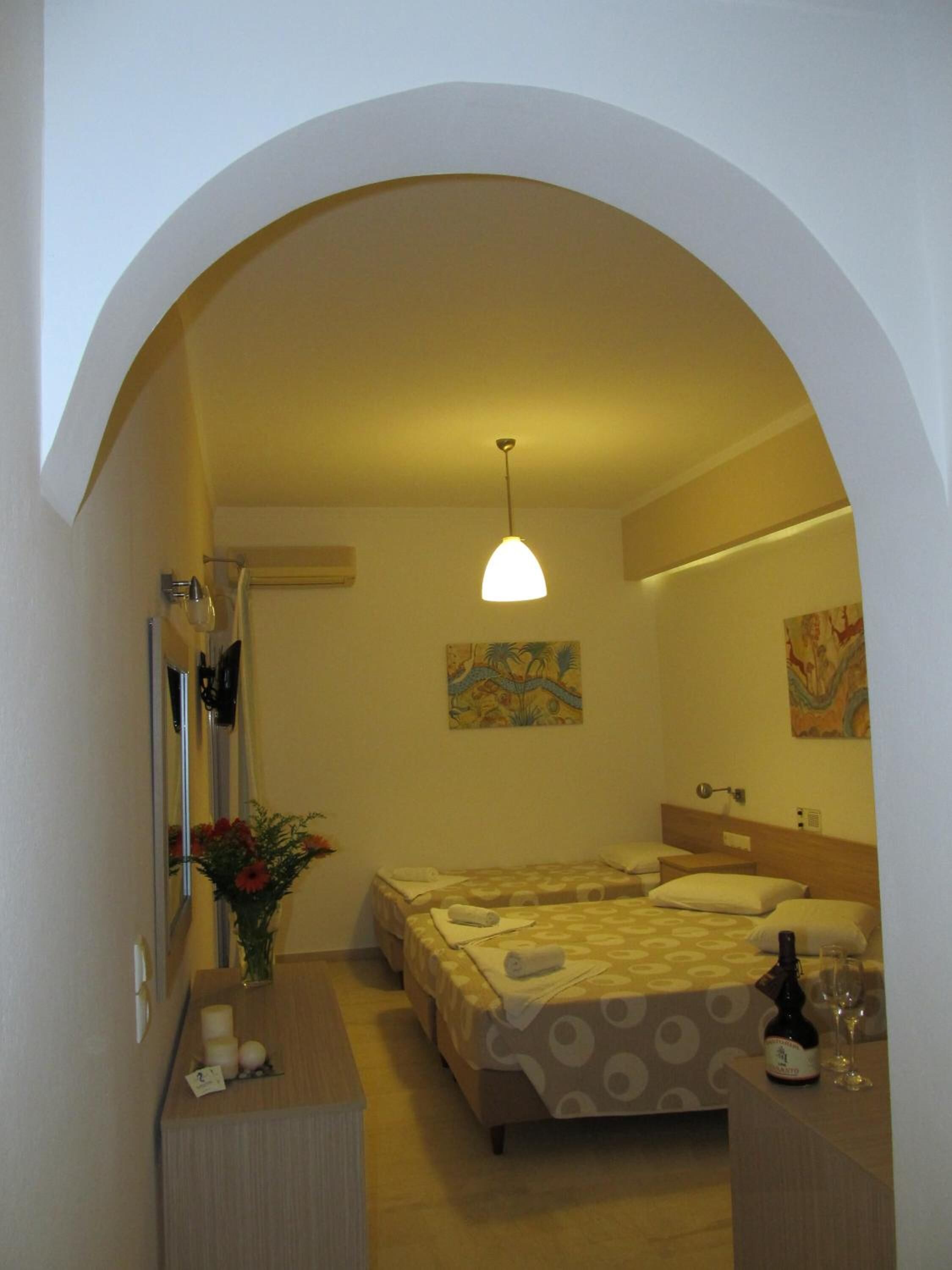 Quarto de hotel com cama, escrivaninha, espelho e um quadro na parede.