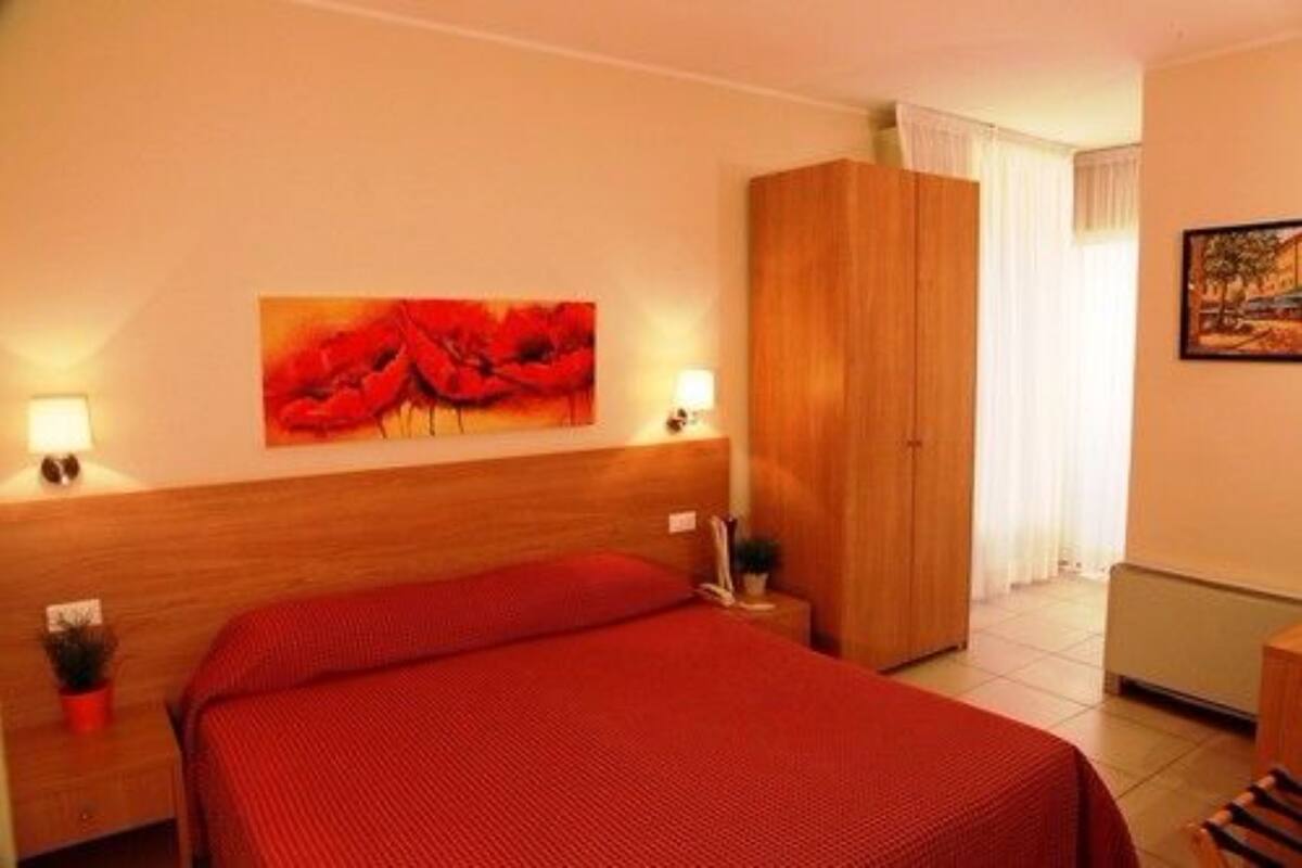 Quarto de hotel com cama, mesa de cabeceira, guarda-roupa e um quadro na parede.