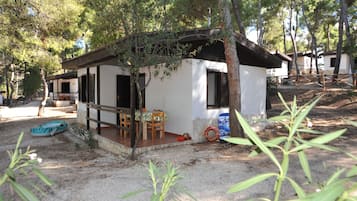 Um pequeno edifício térreo com varanda, cercado por árvores.