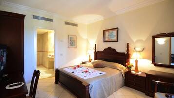 Quarto com cama de madeira, luminárias laterais, um espelho e uma mesinha com abajur.