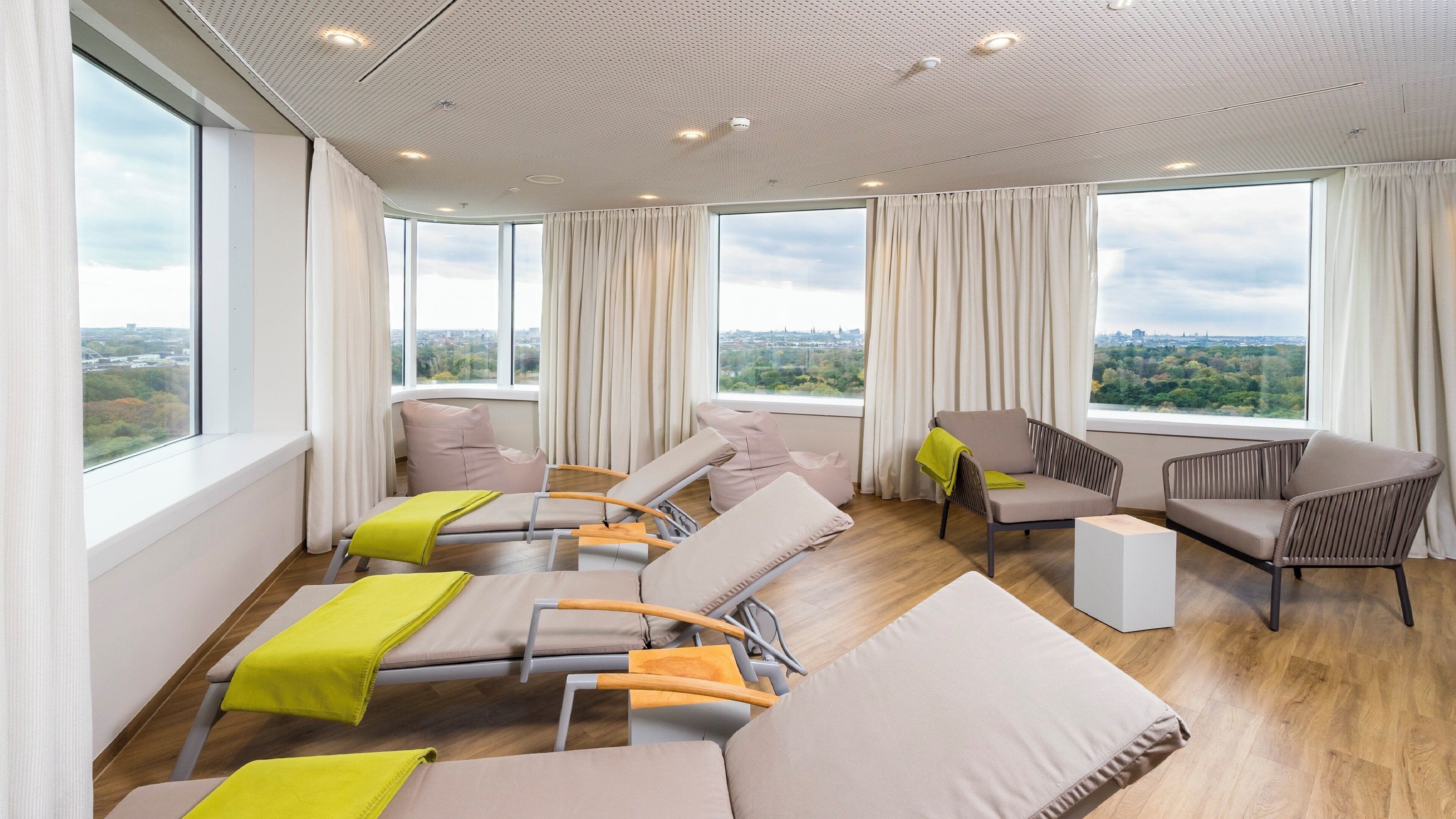 Um lounge moderno com várias áreas de estar, janelas amplas e vista para a cidade.