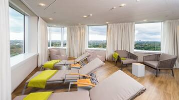 Um lounge moderno com várias áreas de estar, janelas amplas e vista para a cidade.