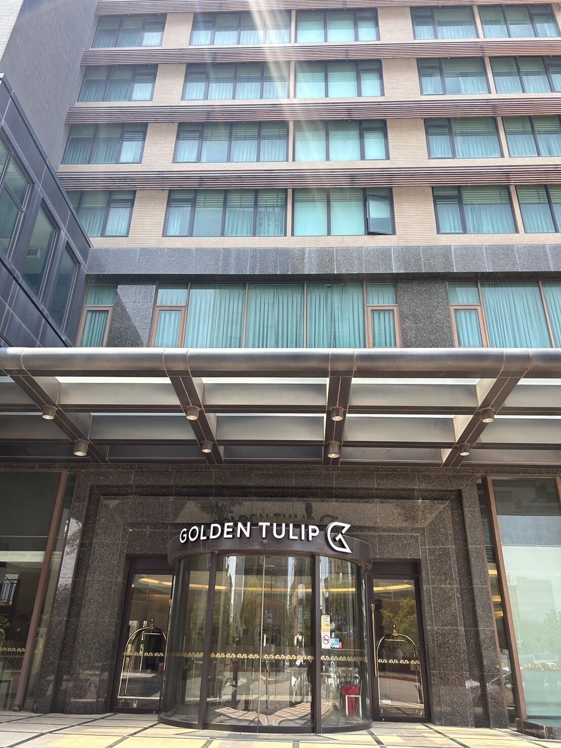 Um edifício moderno com fachada de vidro e uma placa com a inscrição "Golden Tulip".