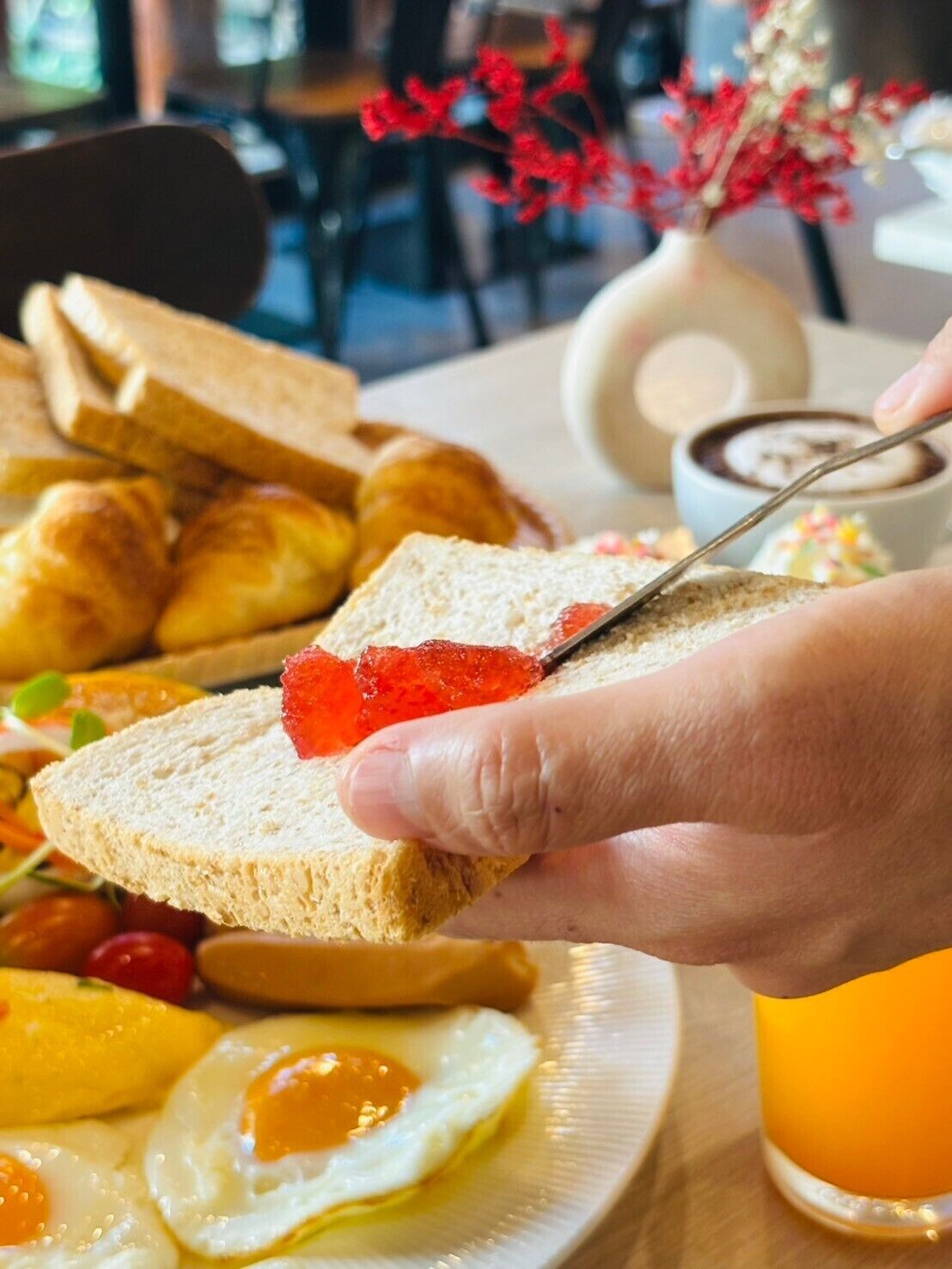 Prato de café da manhã com torradas, geleia, ovos e uma xícara de café.