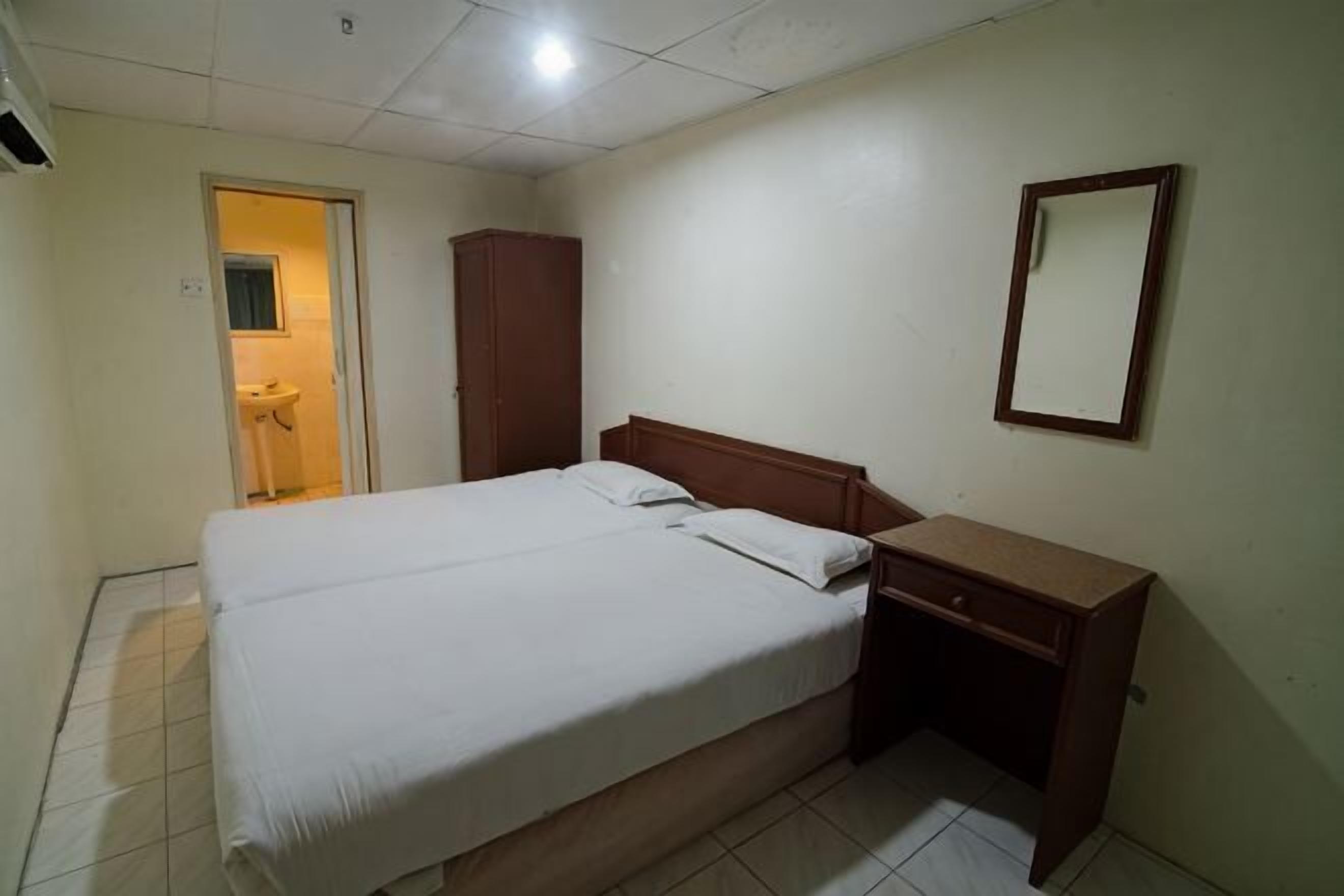 Um quarto com uma cama, uma mesa de cabeceira, um guarda-roupa e um espelho na parede.