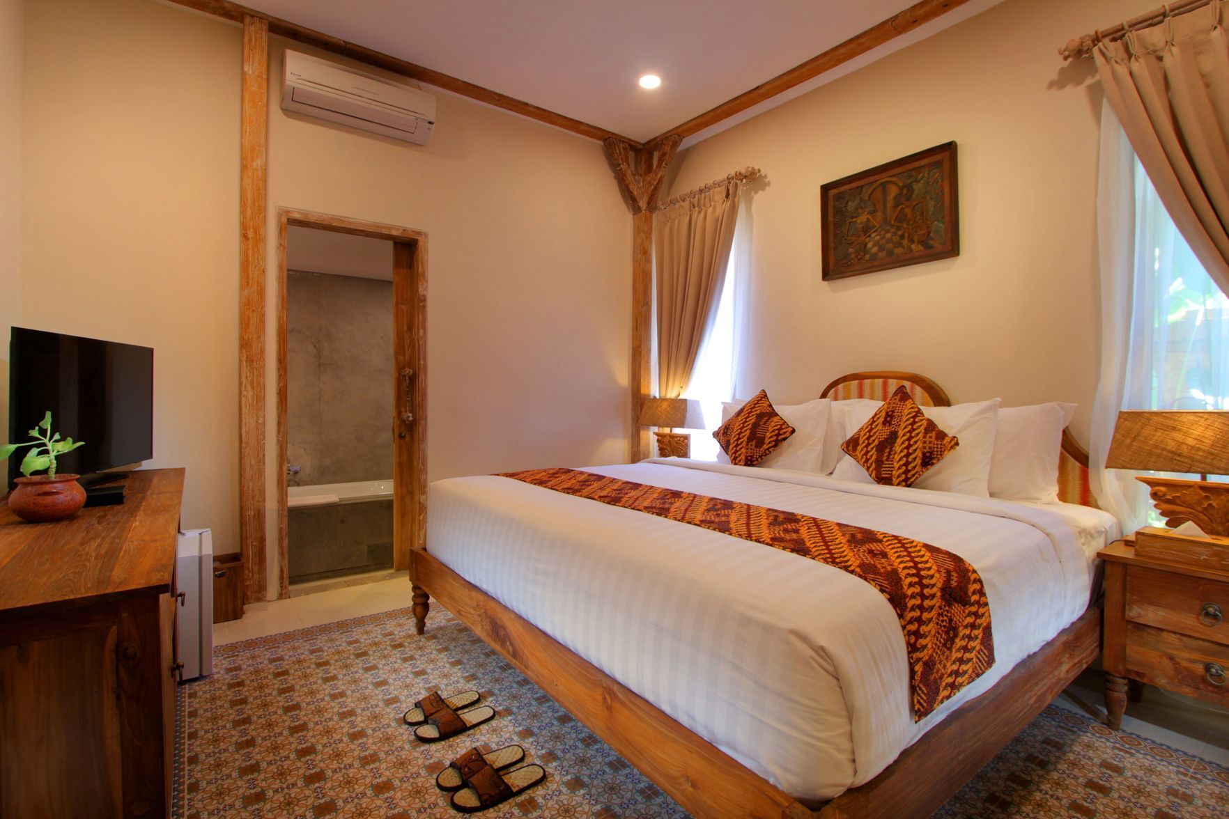 Quarto com cama, televisão, chuveiro e um quadro na parede.