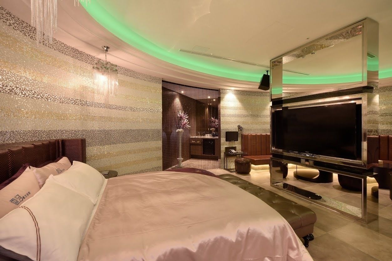 Quarto de hotel moderno com uma cama grande, televisão e banheiro com espelho e pia.