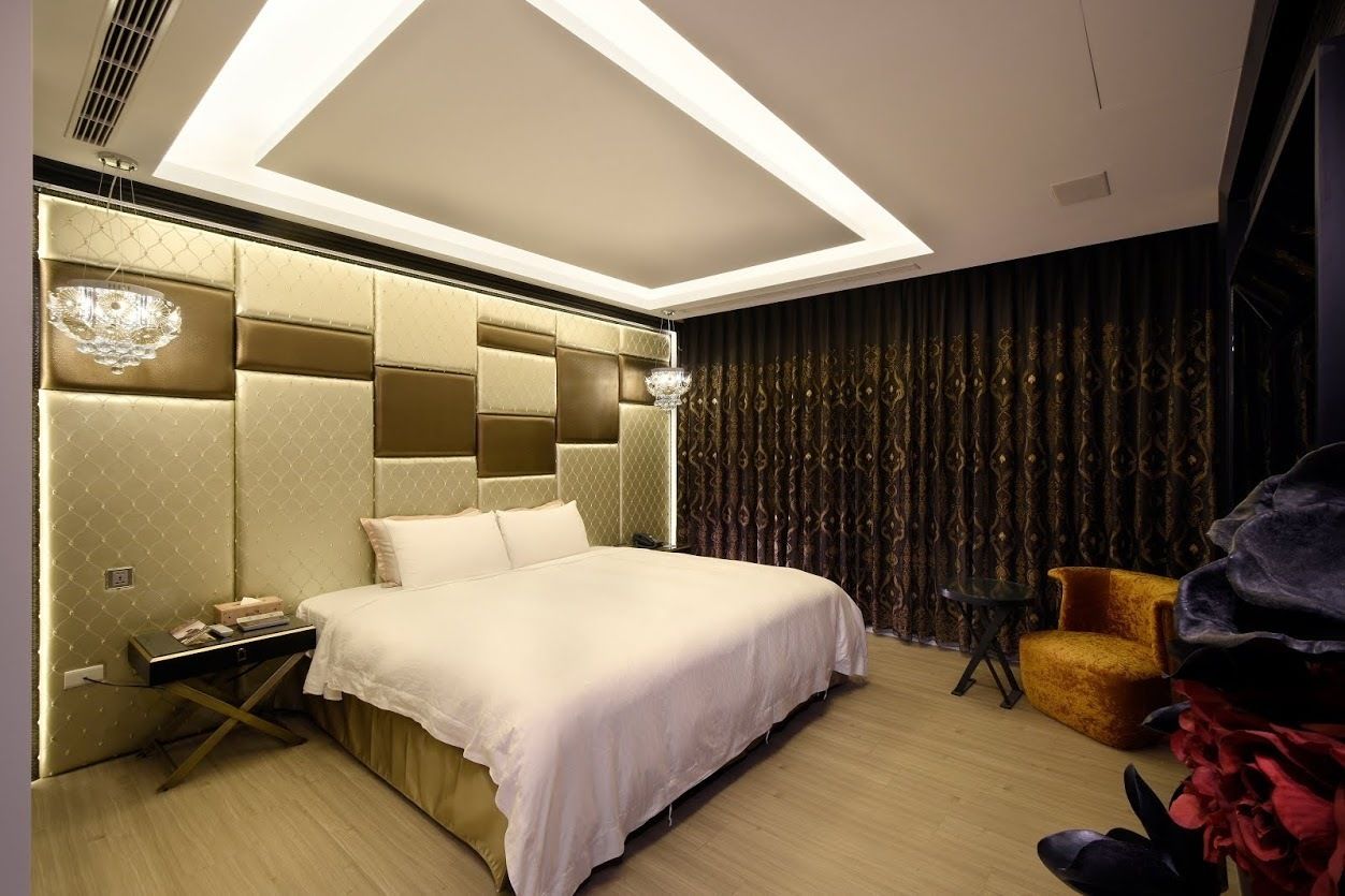 Quarto moderno com uma cama grande, uma mesinha de cabeceira, uma pequena mesa e uma cadeira decorativa.